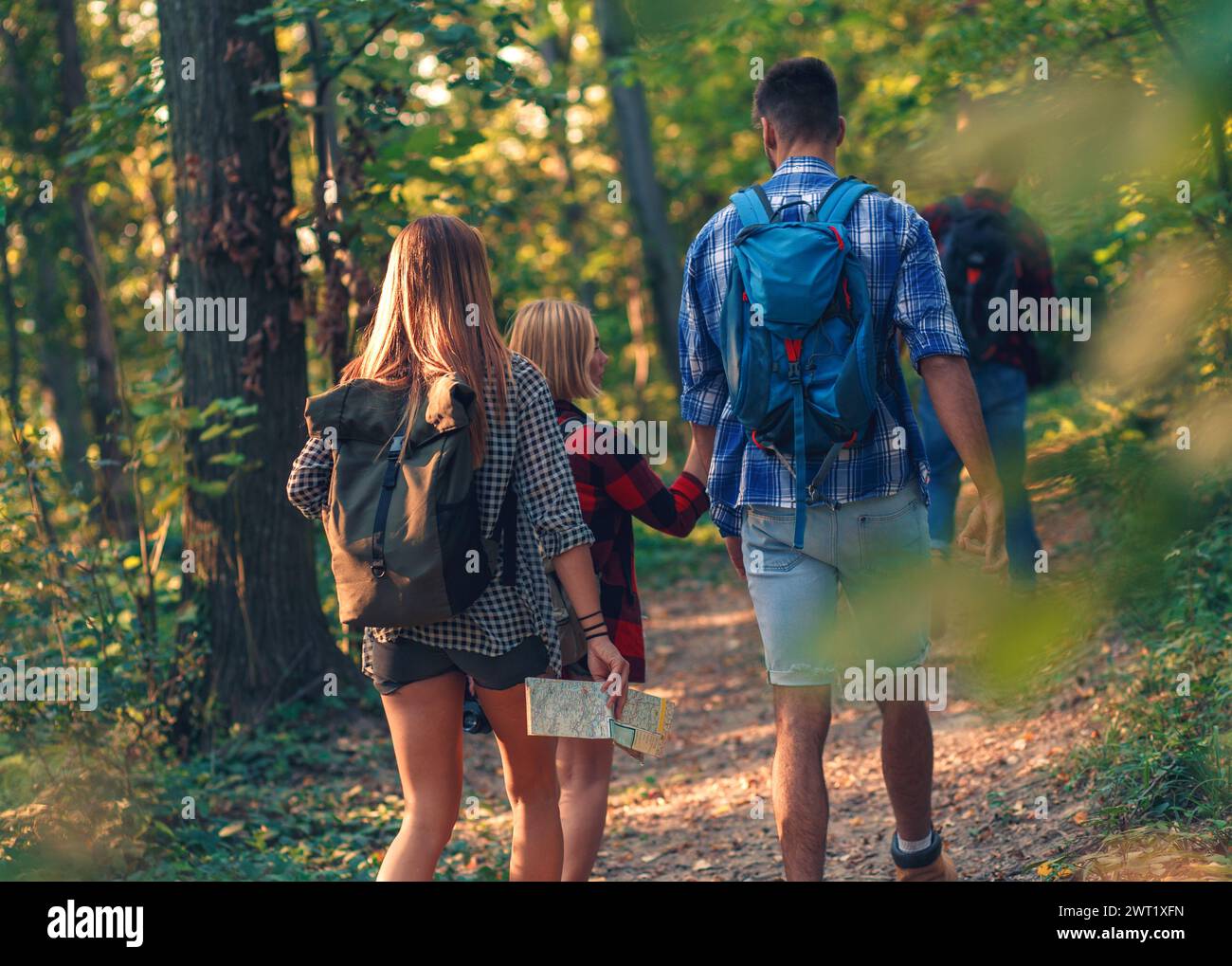 Group of four friends having fun hiking through forest together Stock ...
