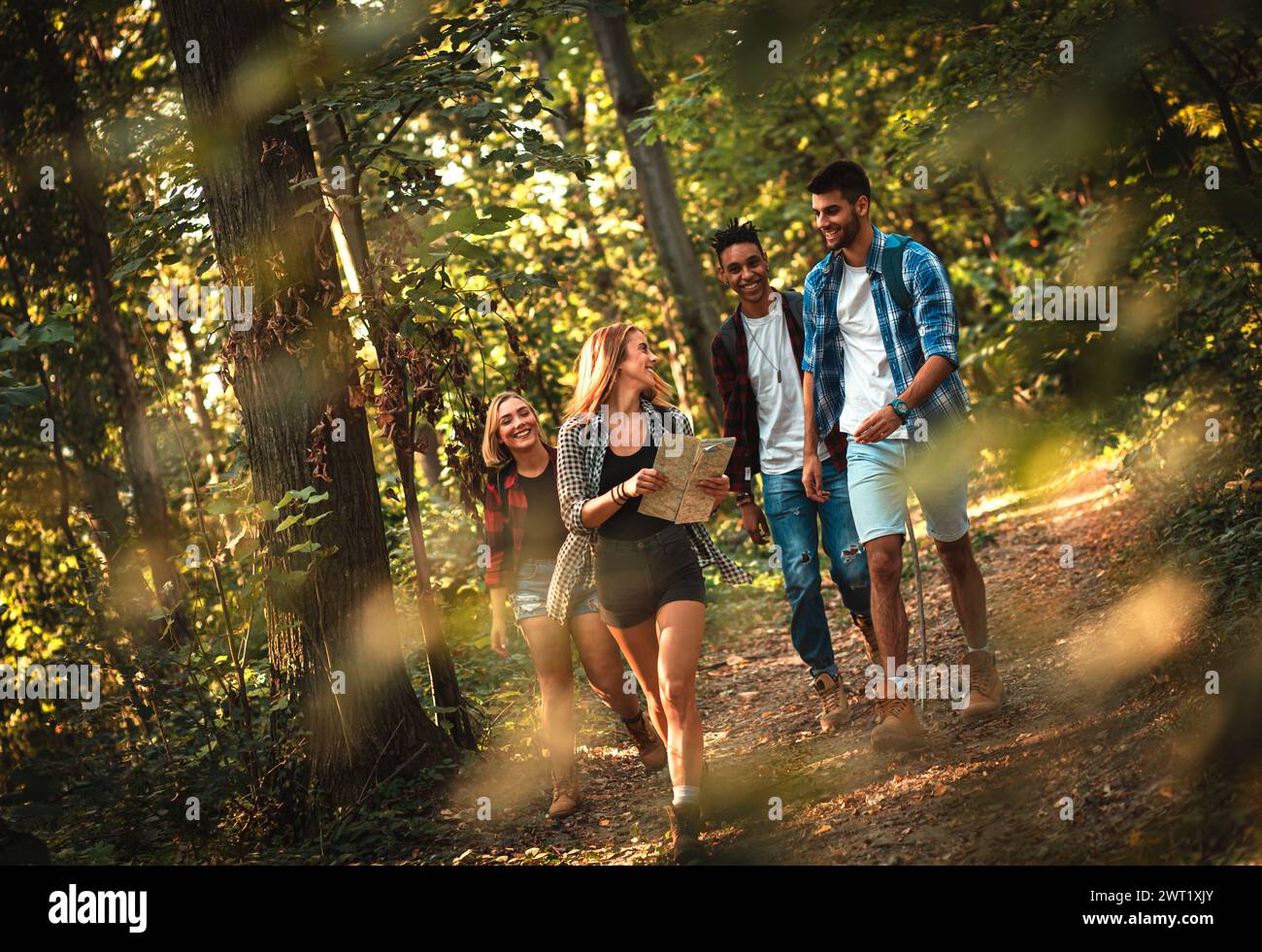 Group of four friends having fun hiking through forest together Stock ...