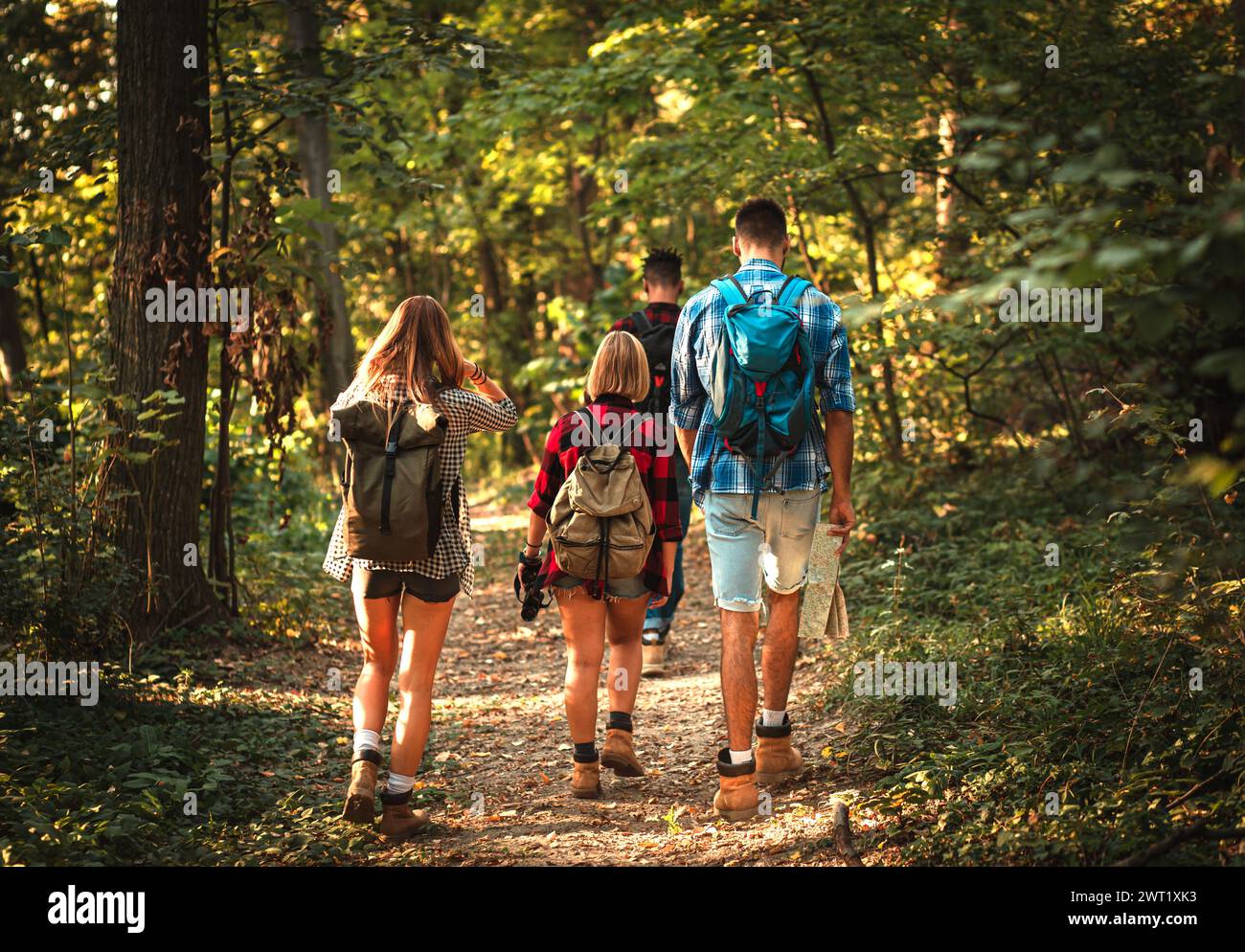 Group of four friends having fun hiking through forest together Stock ...