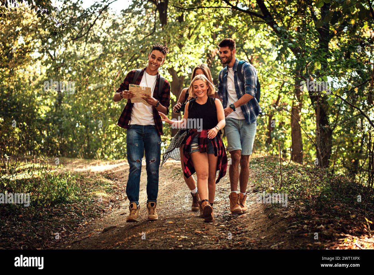 Group of four friends having fun hiking through forest together Stock ...