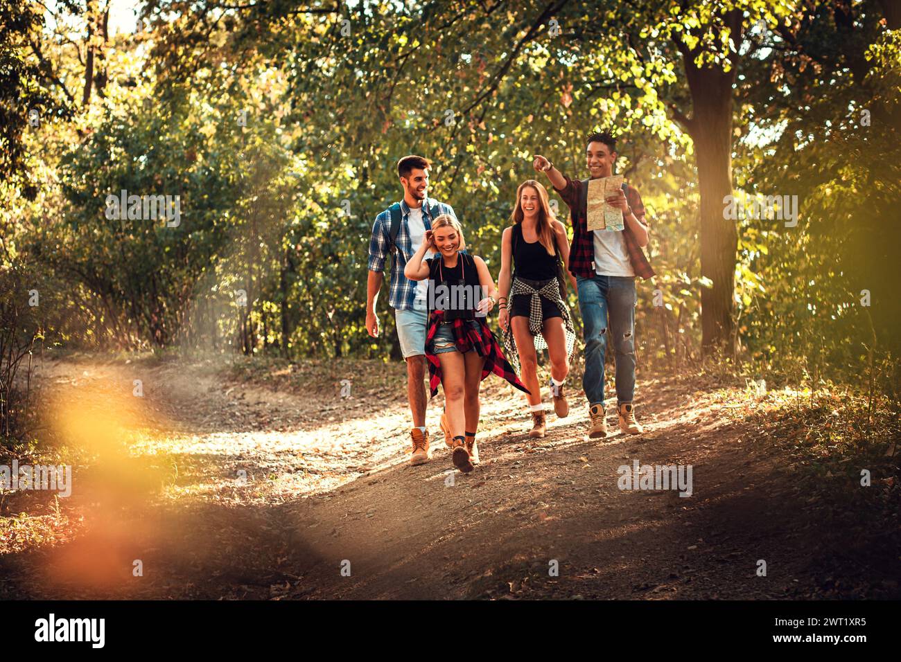 Group of four friends having fun hiking through forest together Stock ...