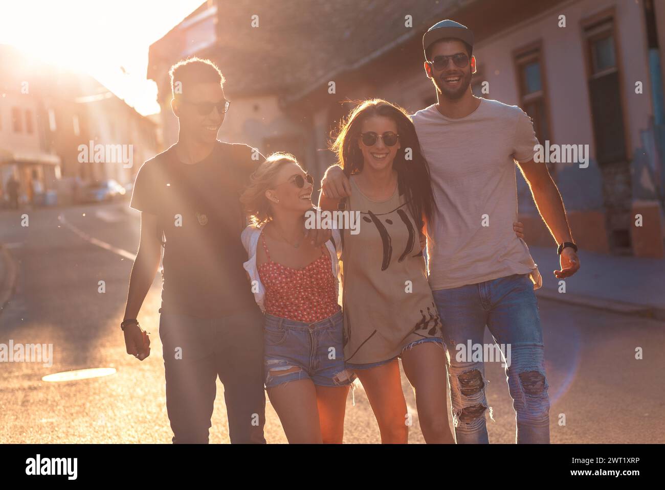 Group of friends walking and laughing at the city street at sunset ...