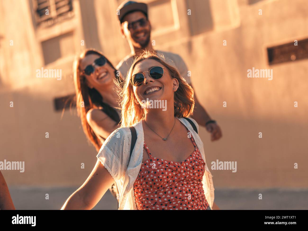 Group of friends walking and laughing at the city street at sunset ...