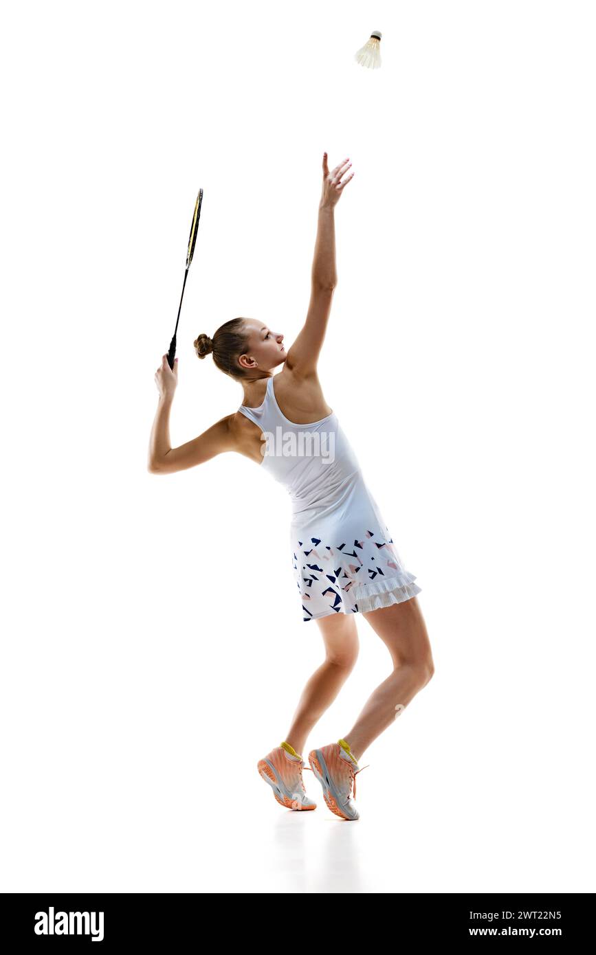 Side view of sportive young girl, badminton player in motion serving ...