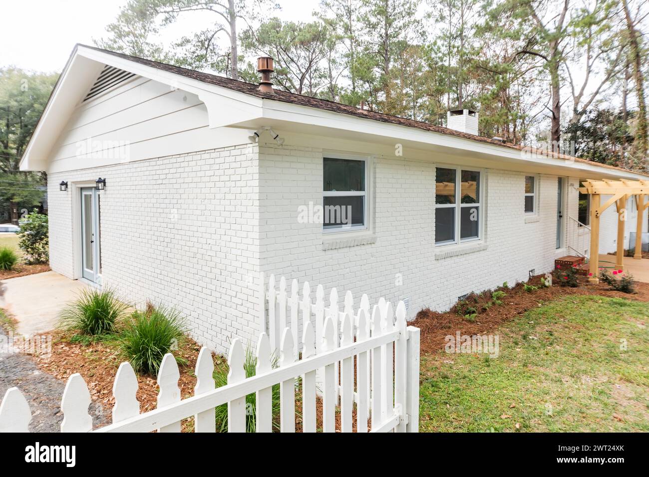 Side view of a white ranch house with a short white picket fence ...