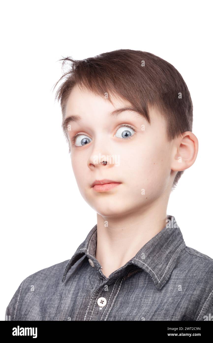 A young boy wearing denim shirt looks surprised with eyes wide open and ...