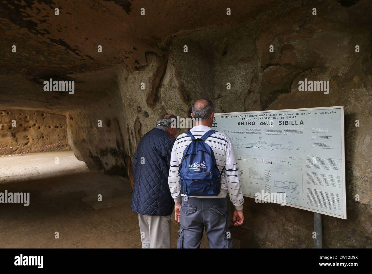 Two tourists in front of the entrance to the cave of the Sibilla Cumana ...
