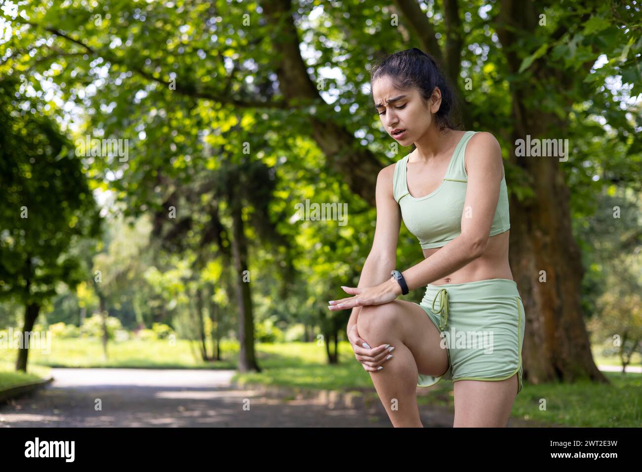 Indian young girl standing in a park in a tracksuit and holding her ...