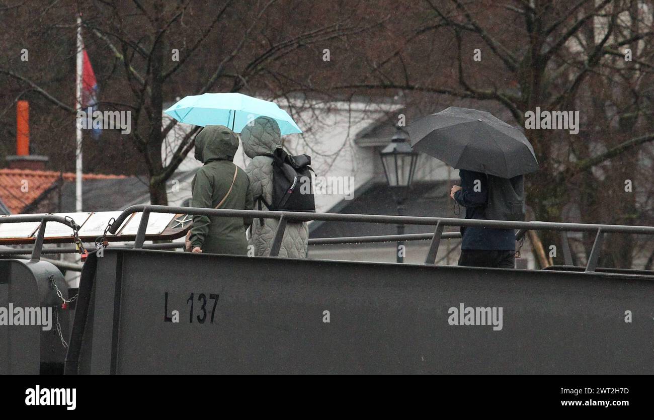 Drei Passanten gehen bei Hamburger Schietwetter über eine Brücke am ...