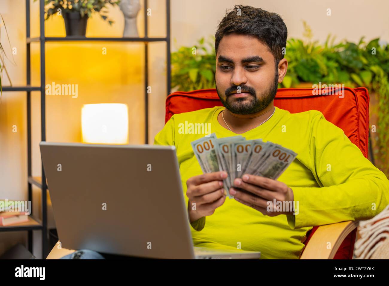 Planning budget. Rich happy Indian man counting money cash use laptop ...