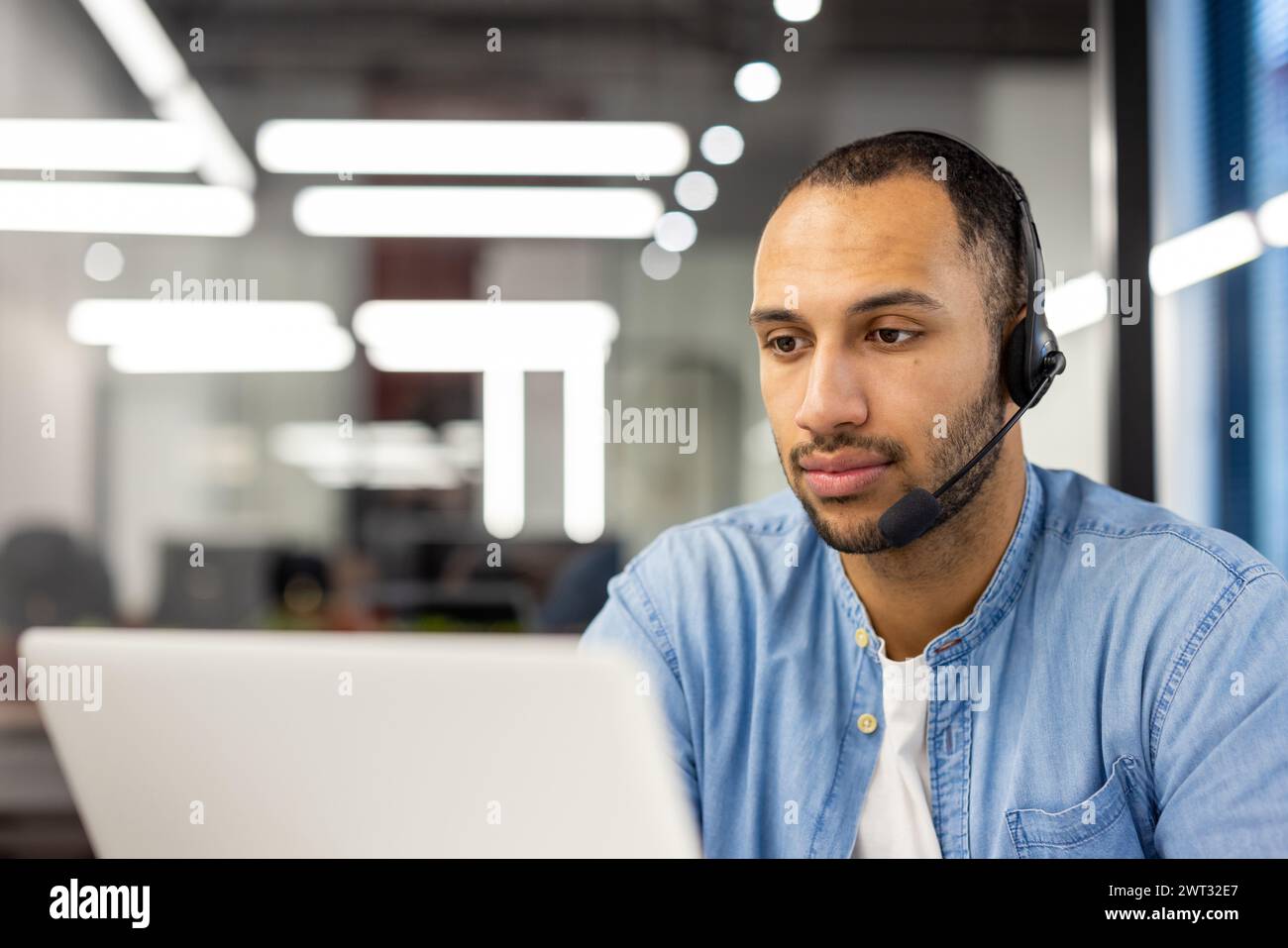 A concentrated male worker wearing a headset while being engaged with ...