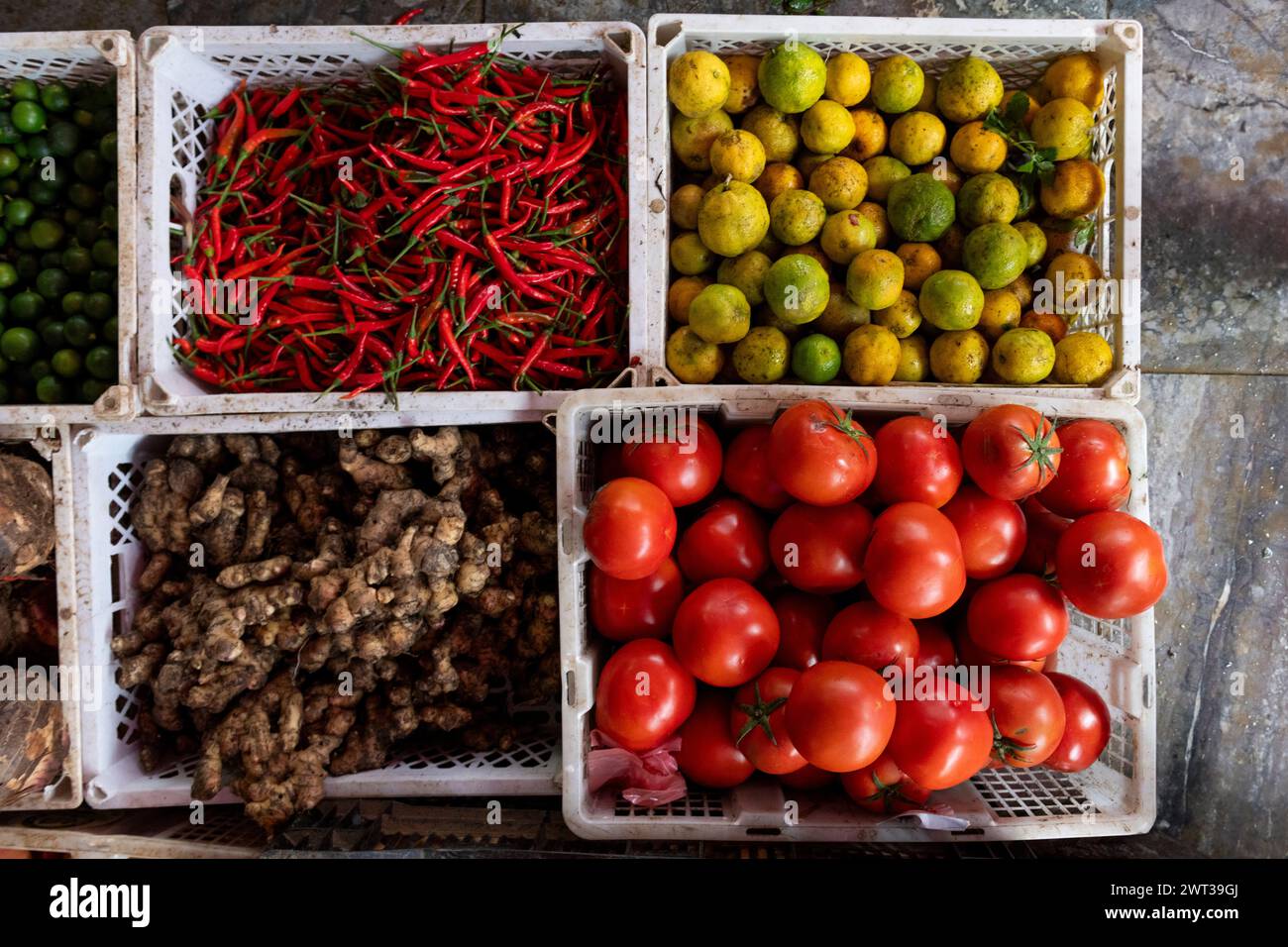 Overhead view of baskets of fresh red chile peppers, lemons, ginger ...