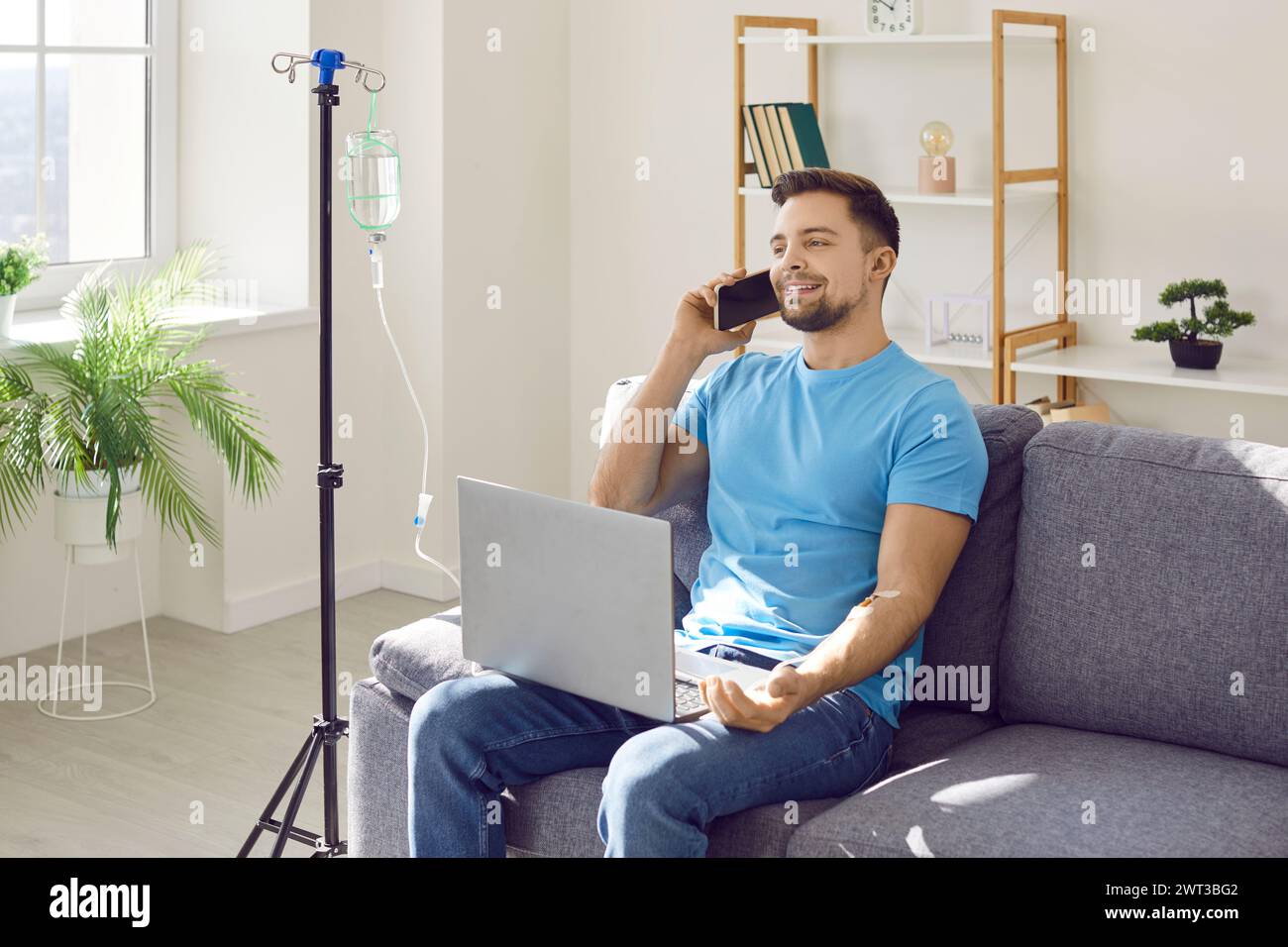 Young man receiving intravenous vitamin therapy while talking on phone ...