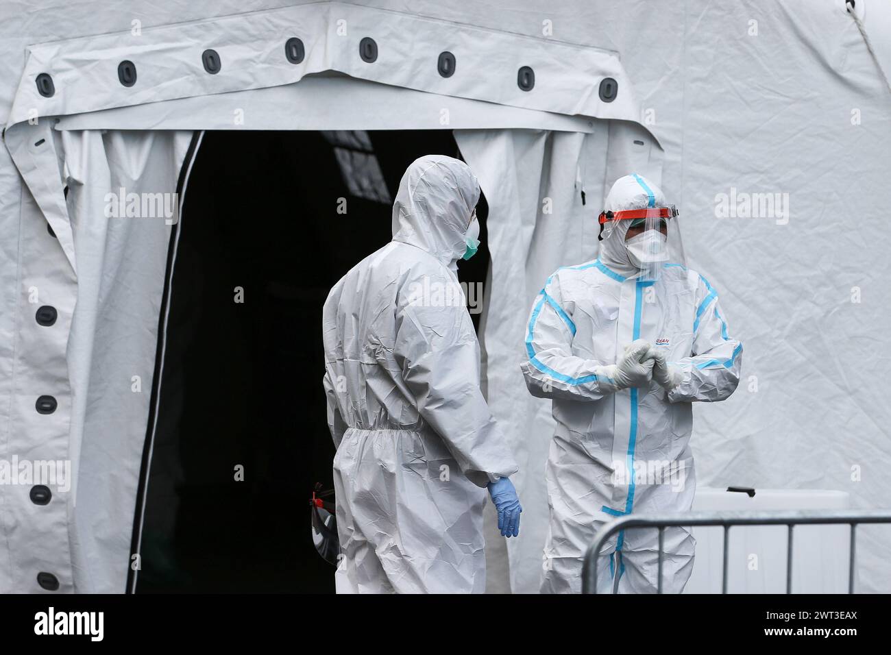 Two doctors dressed in overalls and masks to protect himself, in front ...