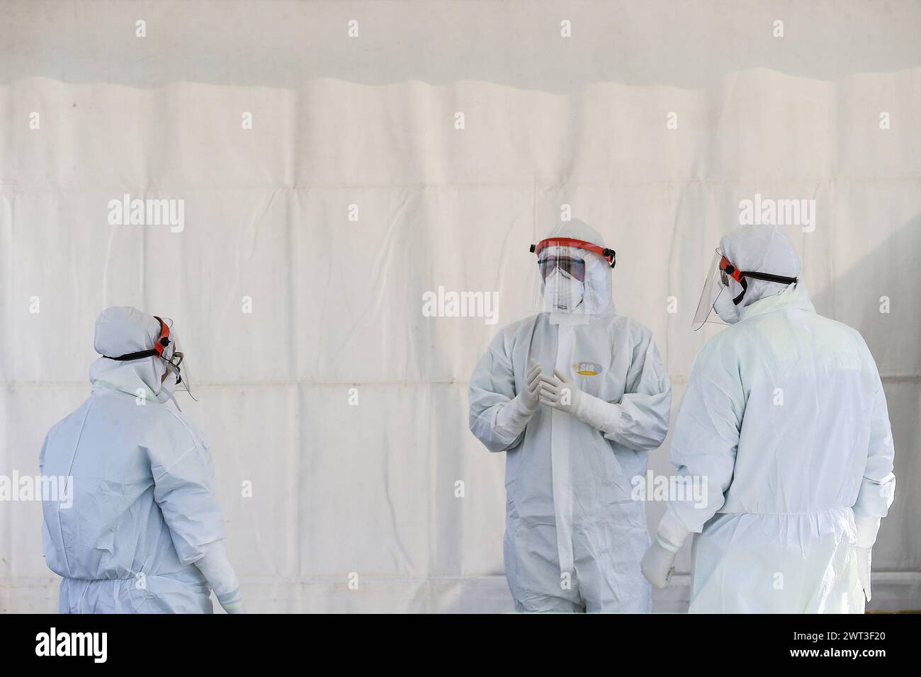 Three doctors dressed in overalls and masks to protect himself, waiting ...
