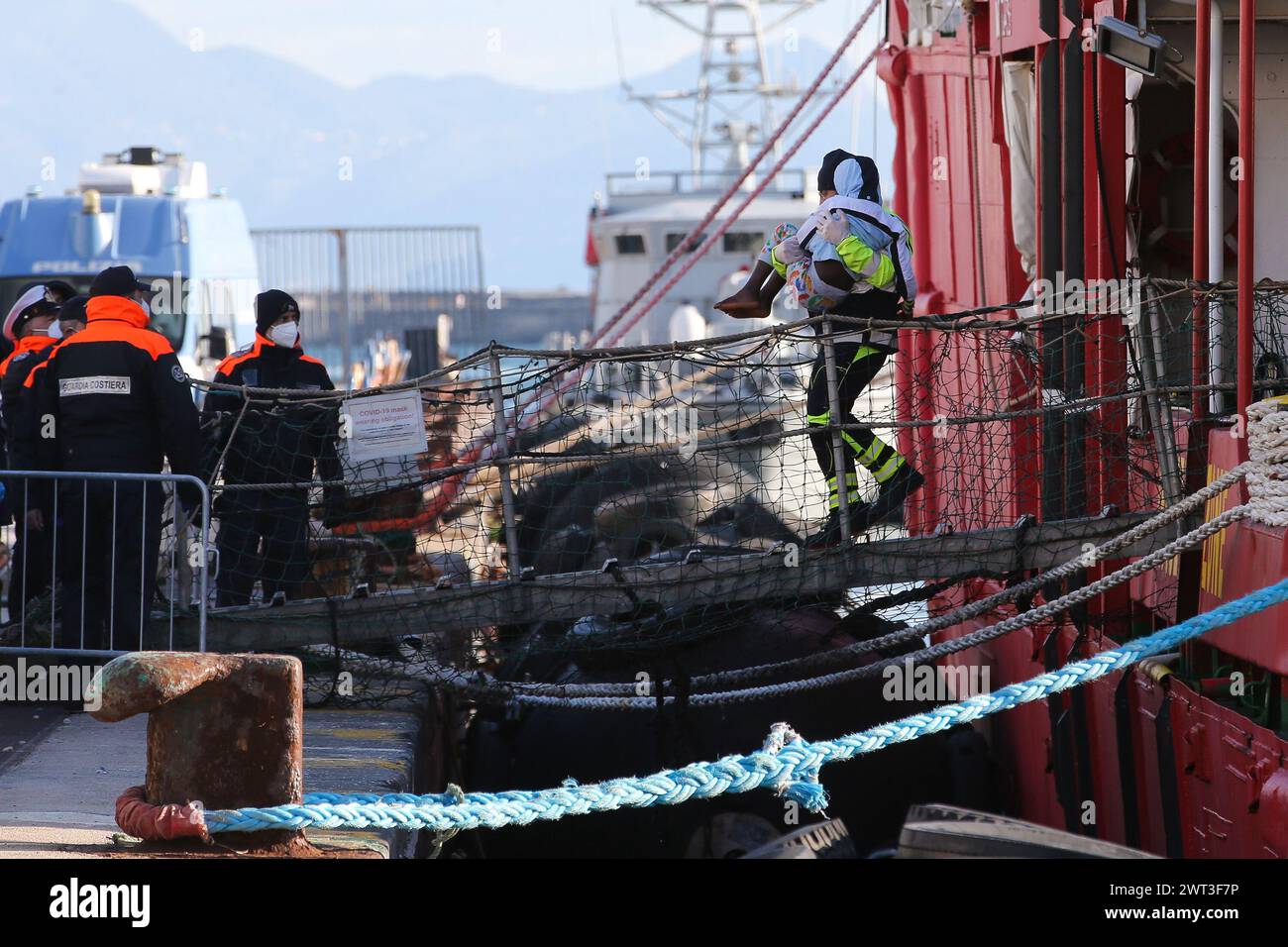 A migrant, carried in the arms of a rescuer, disembarks in Naples, from ...