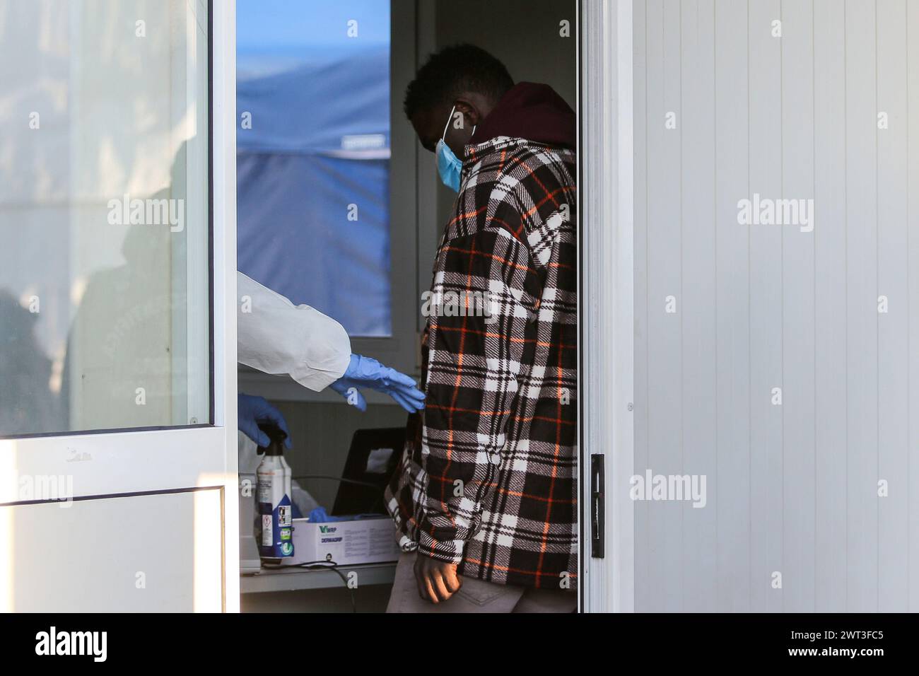 A migrant during checks after landing in Naples, from the Sea-Eye 4 ...
