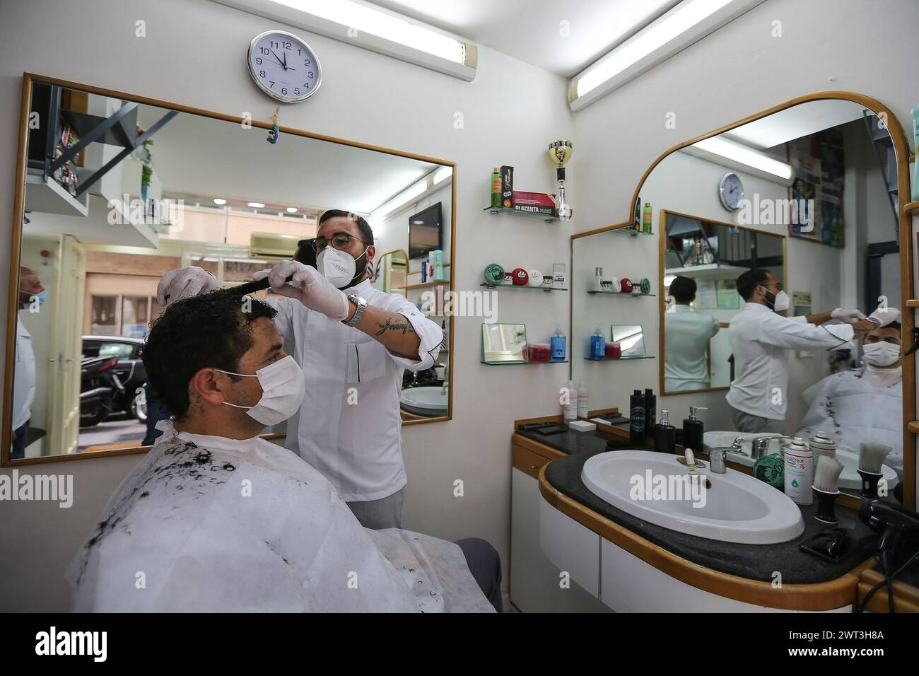 A barber cuts the hair of a customer in his barber shop reopened the ...