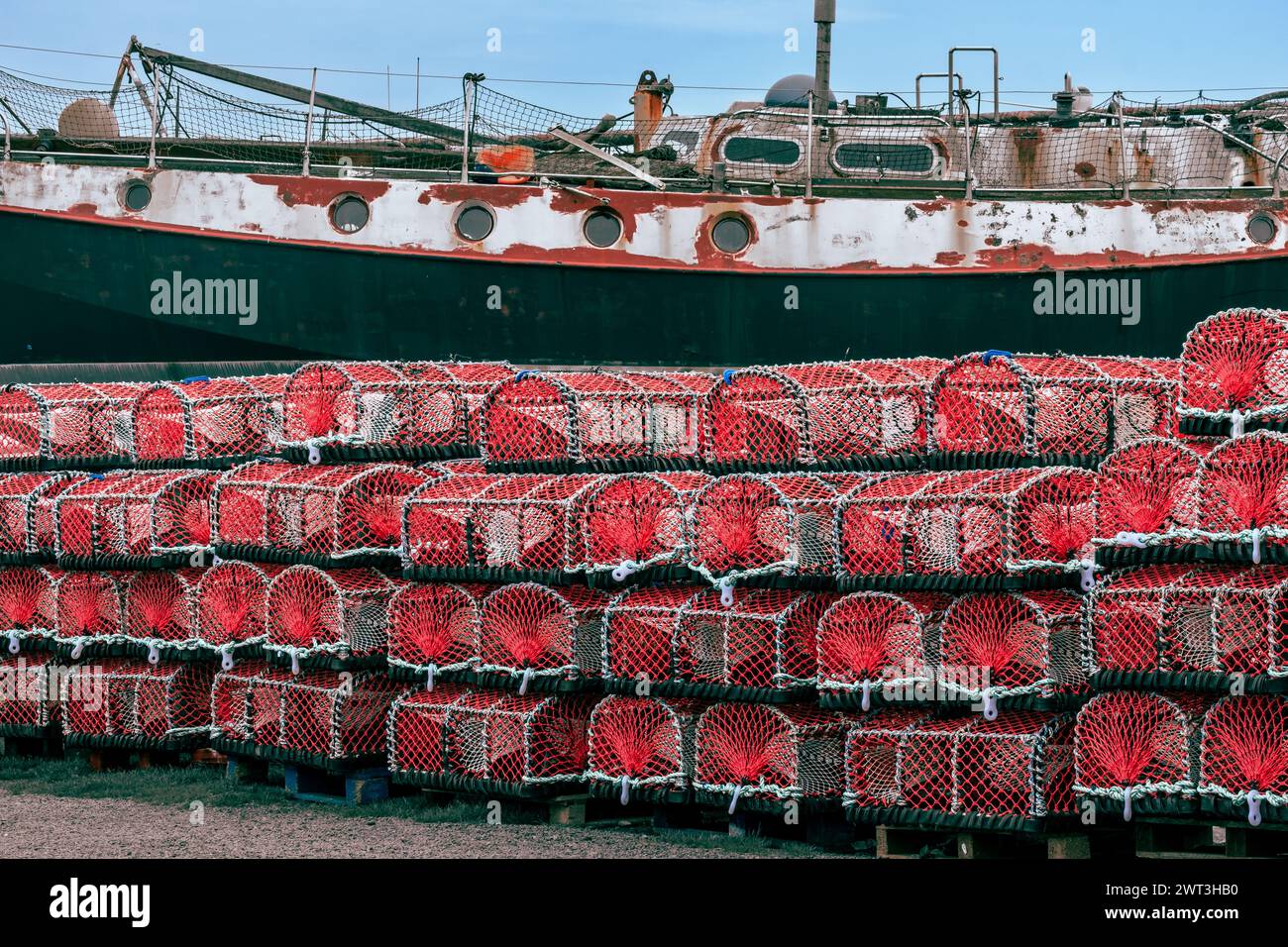 Old rusting fishing boat with multiple red net lobster pots in front of ...