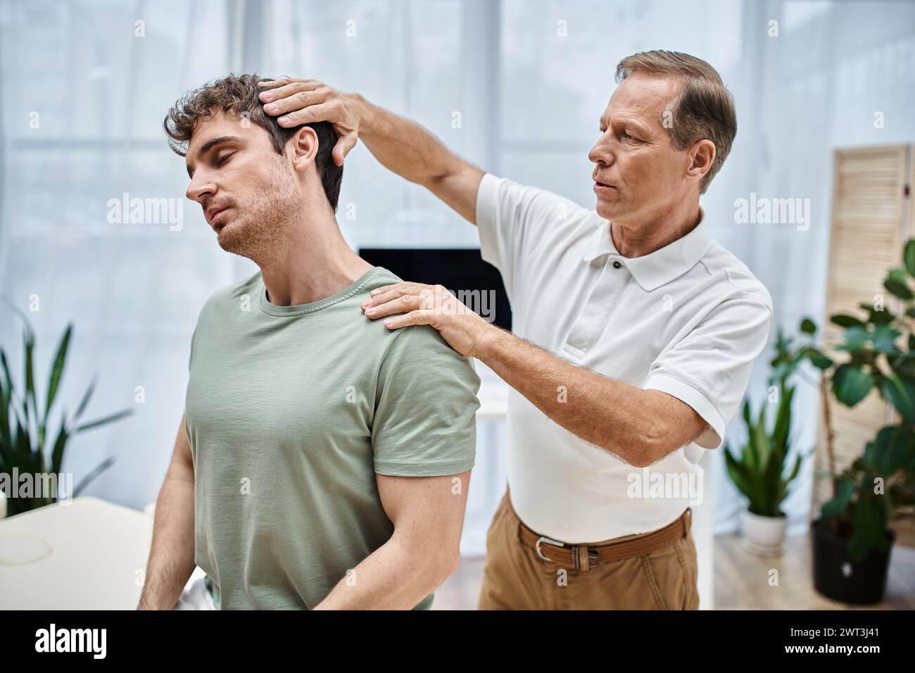 good looking doctor in medical uniform massaging neck of his patient ...