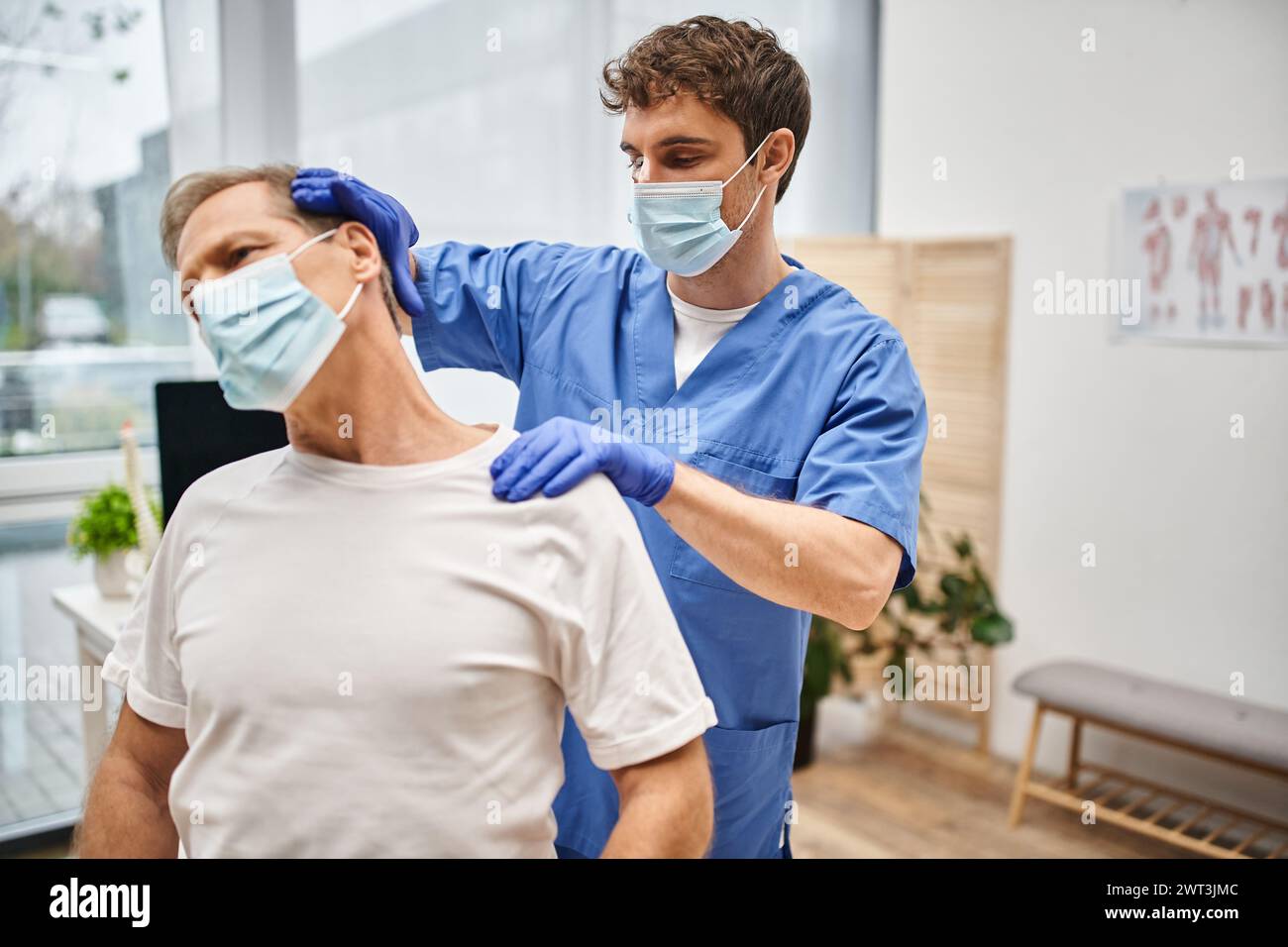 dedicated good looking doctor with mask stretching his patient during ...