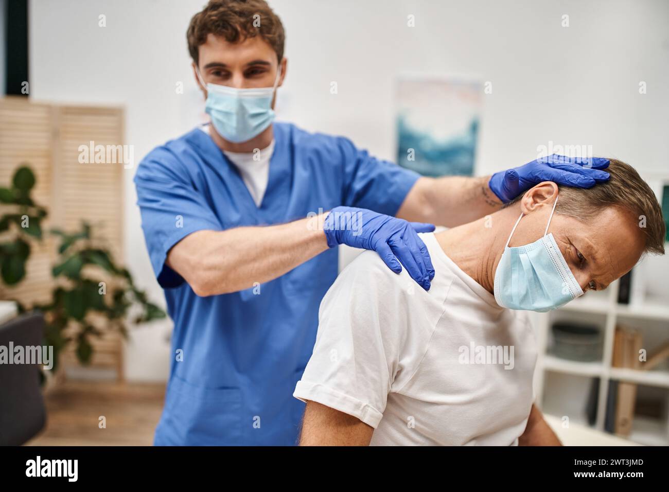 hardworking doctor with mask and gloves helping his patient to stretch ...