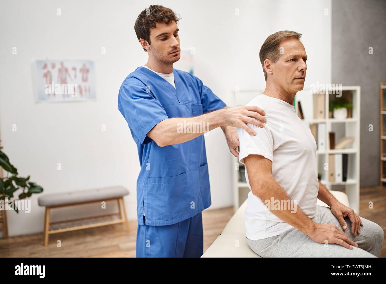 good looking doctor in medical robe rehabilitating his mature handsome ...