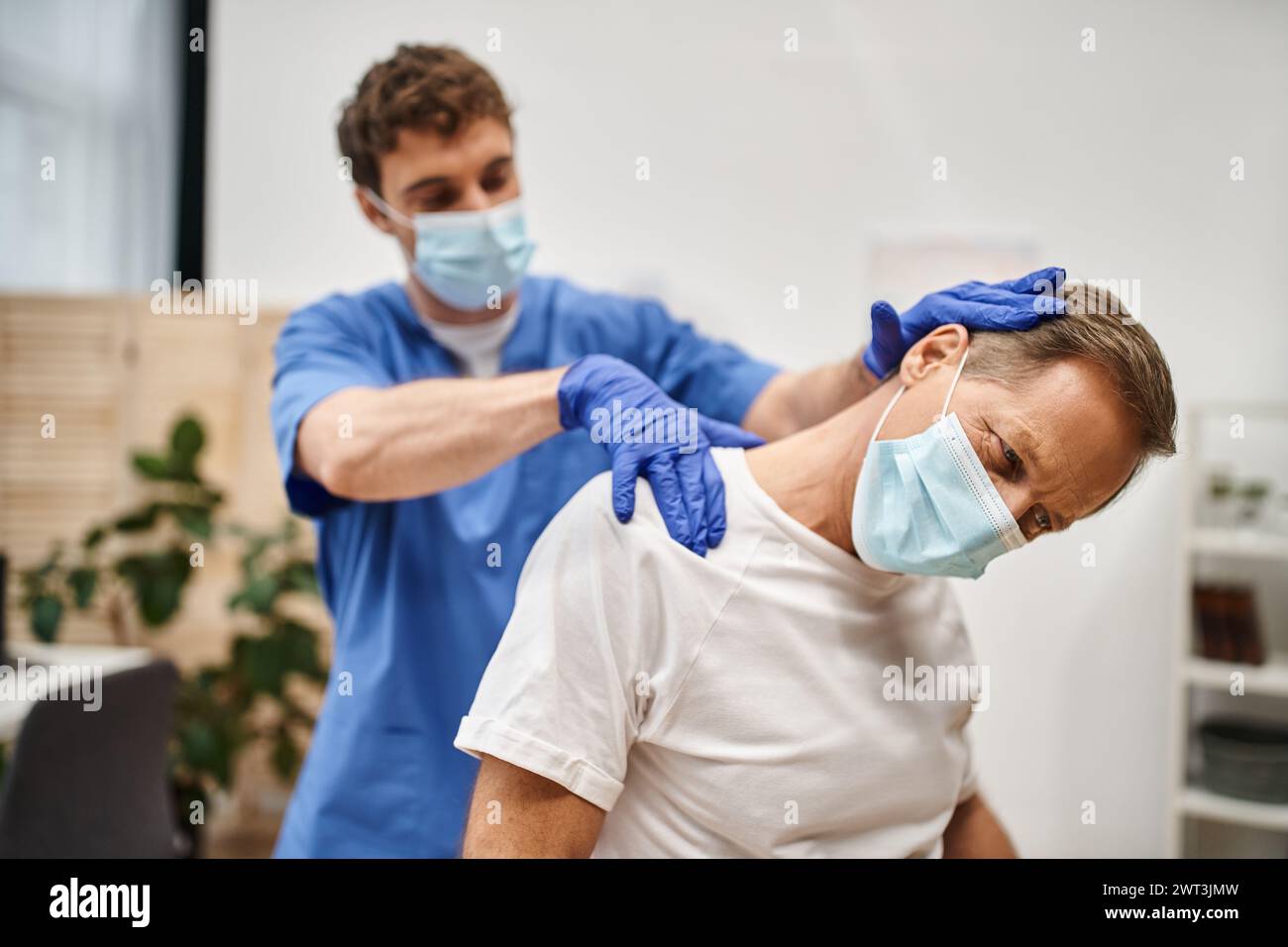 dedicated doctor with mask and gloves helping his patient to stretch ...