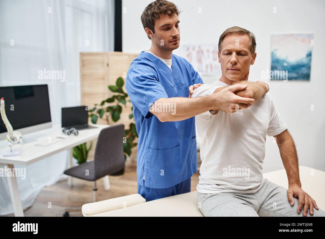 mature handsome patient in casual attire stretching his muscles with ...
