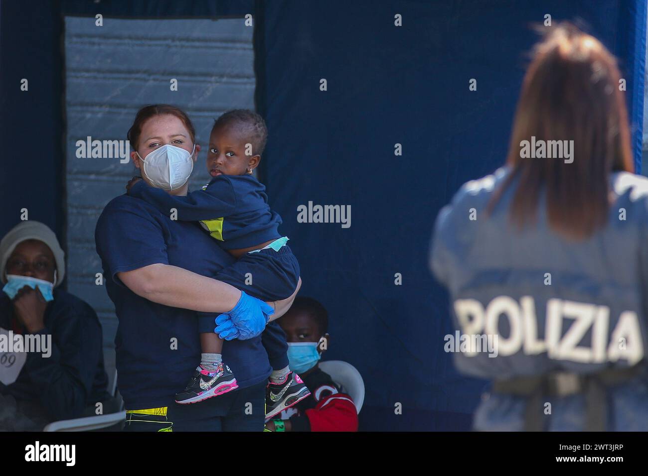 A migrant child with a rescuer during the checks after disembarking in ...
