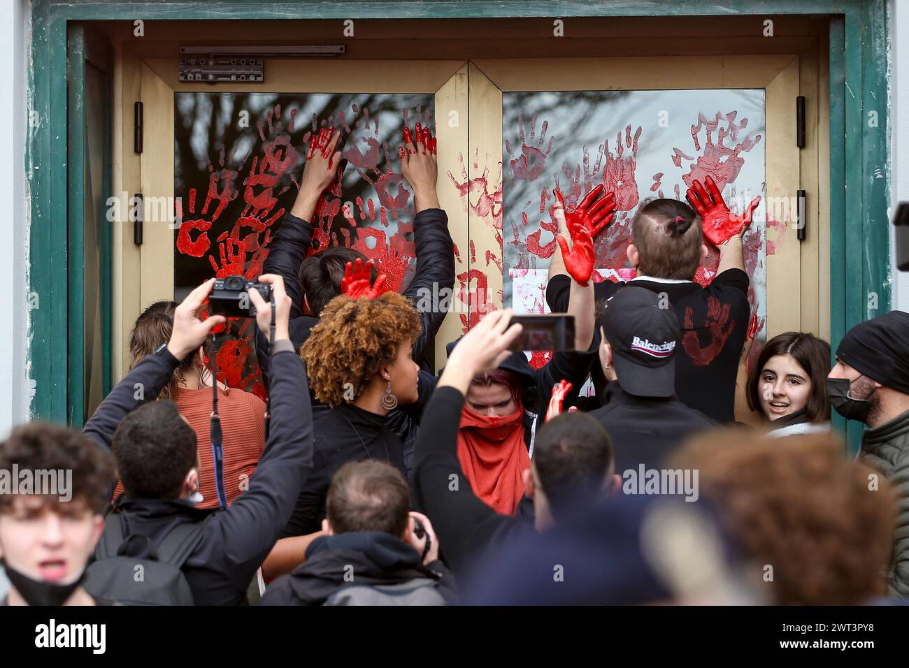 Students dye their hands red, to symbolize blood, and stain the door of ...