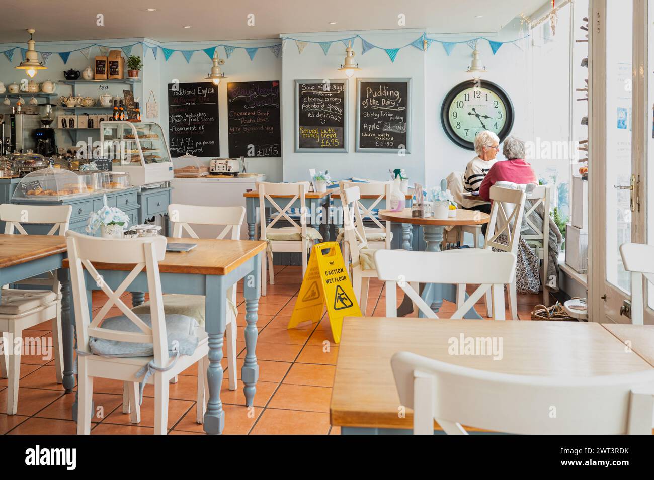 Interior of a Devon cafe with a Caution Wet Floor sign and two ladies ...