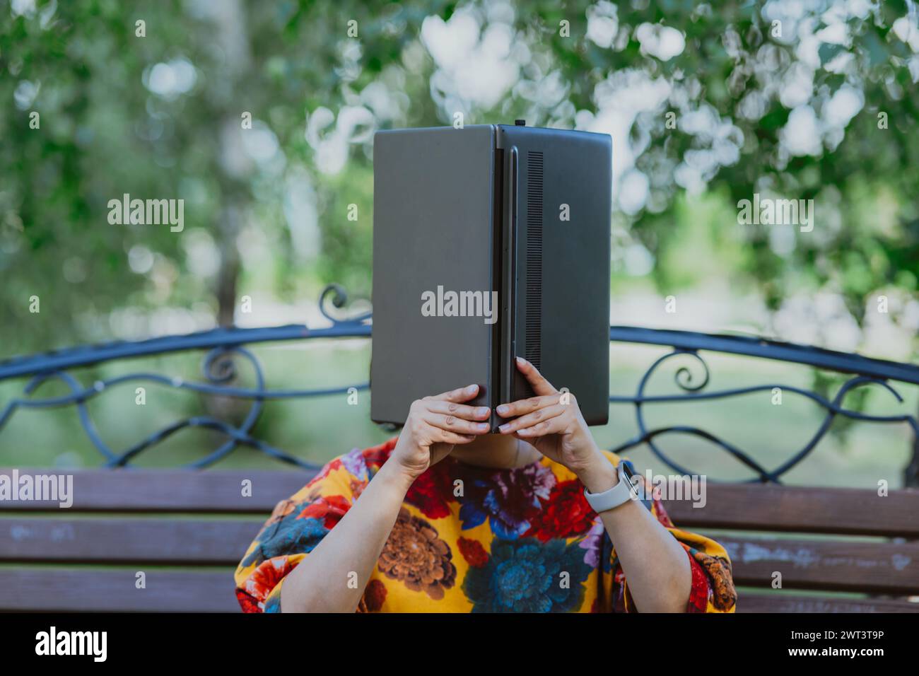Woman using her laptop as an open book, covering her face Stock Photo ...
