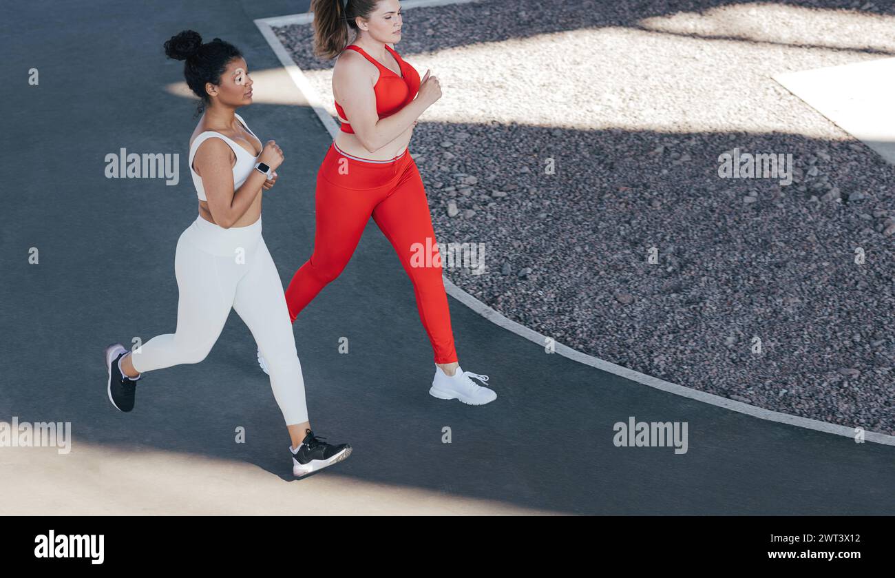Shot from above of two females running together outdoors. High angle of ...