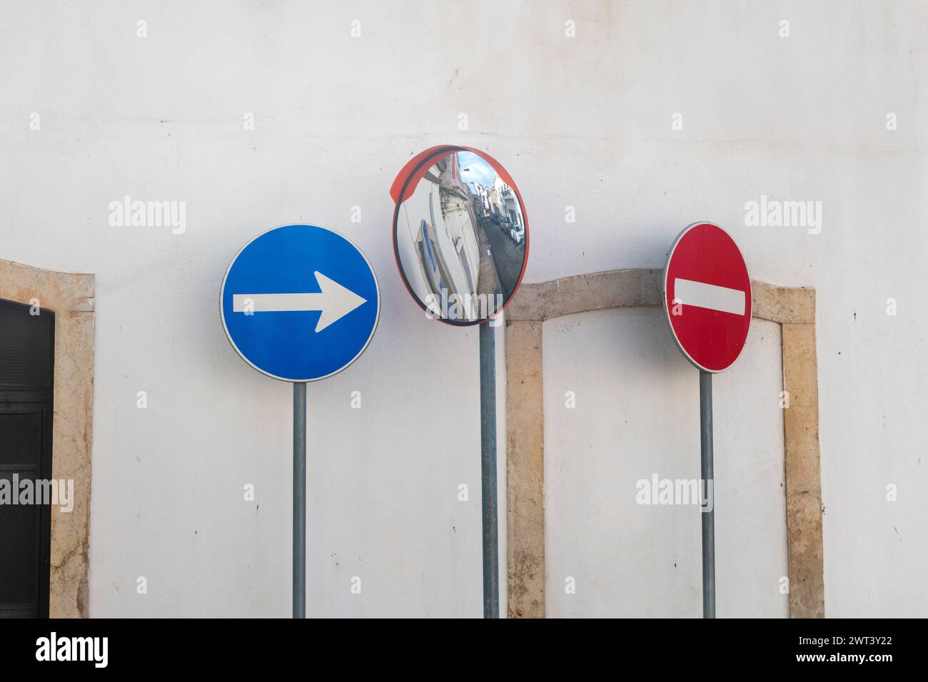 turn right and stop road signs with a circular mirror by a white wall ...