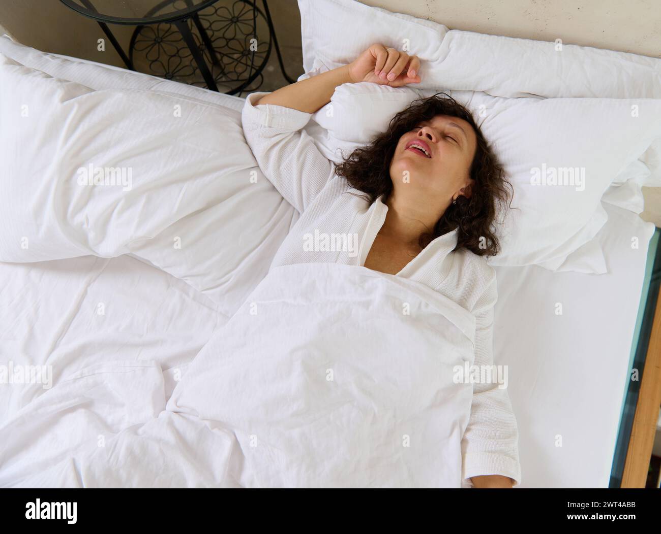 View from above of a young woman snoring while sleeping in her bed ...