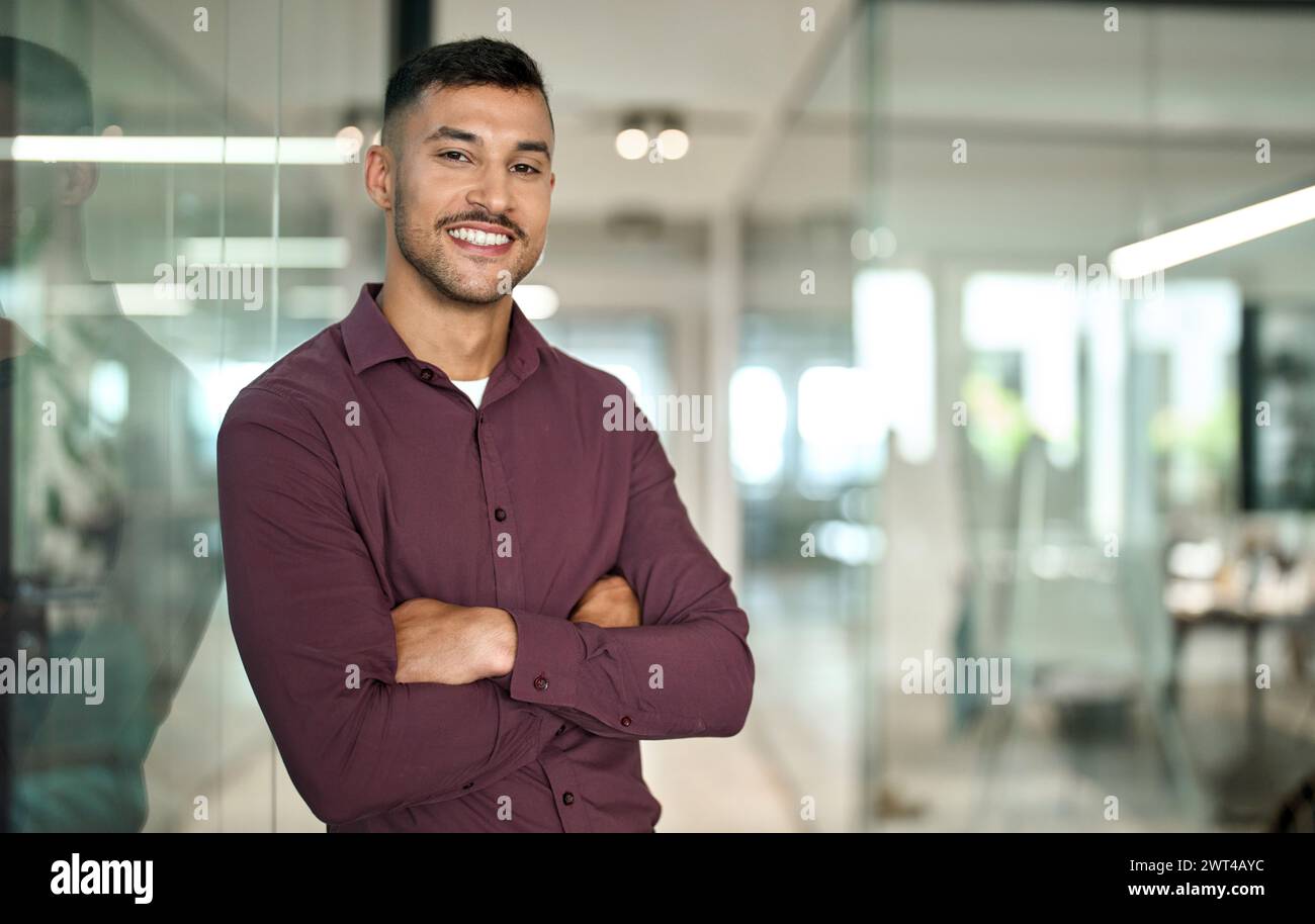 Confident young Latin business man standing arms crossed in office ...