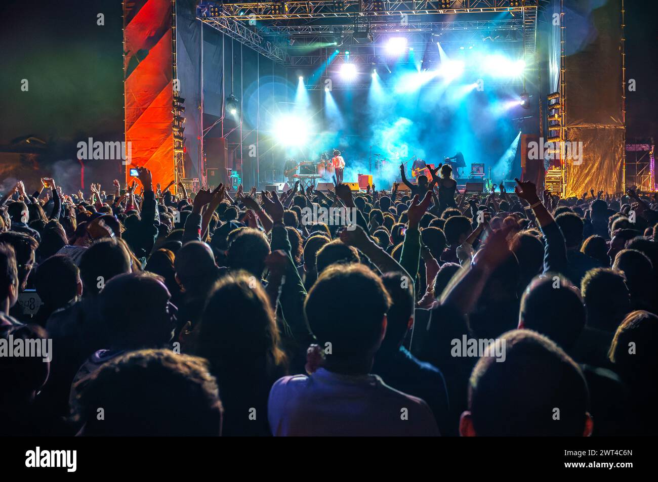 Crowd enjoying a night-time rock concert under vibrant stage lights ...