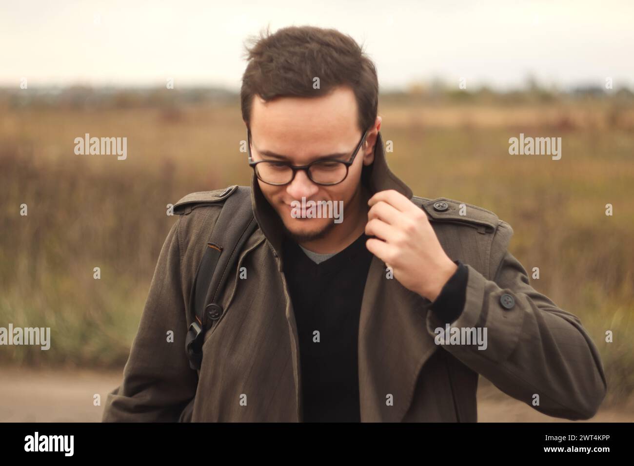 Stylish young man on autumn background. Man feeling freeze and wrap up ...