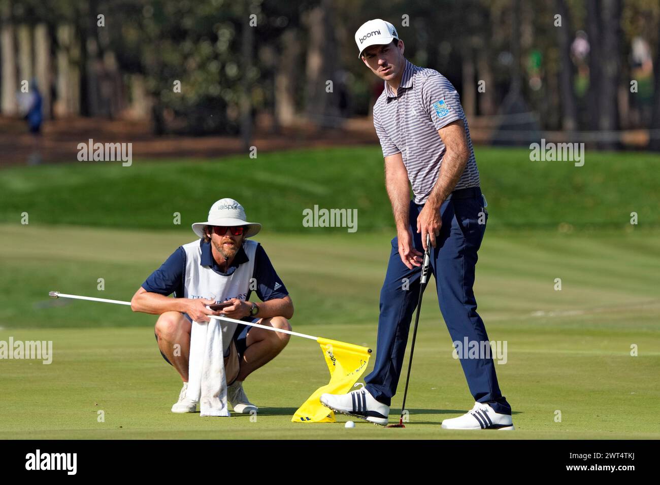 Nick Taylor, right, of Canada, lines up a putt on the 11th green with ...
