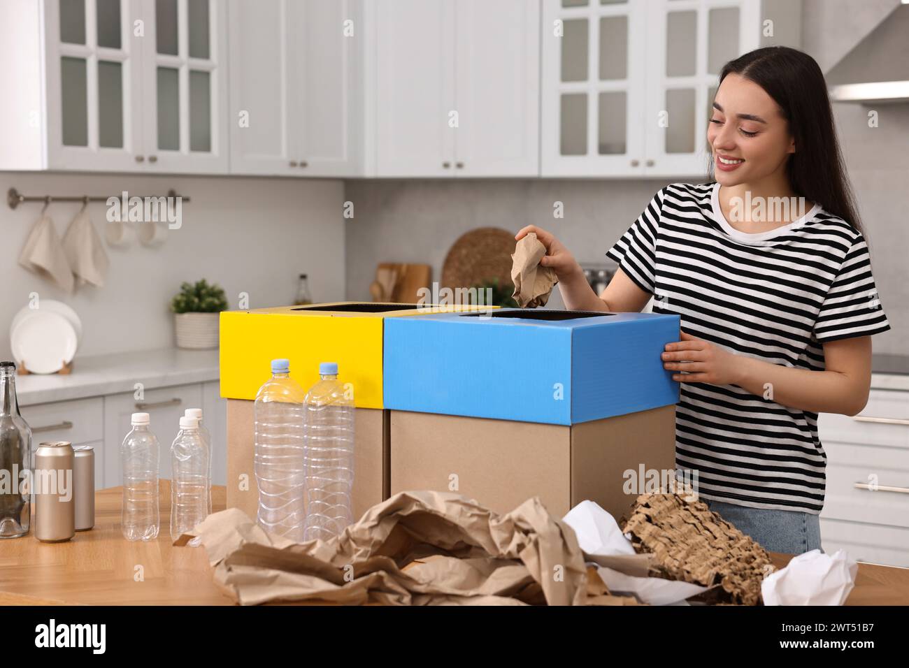 Garbage sorting. Smiling woman throwing crumpled paper into cardboard ...