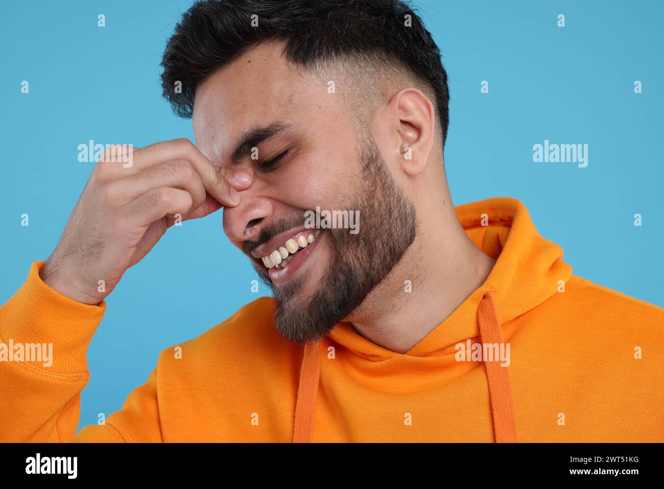 Handsome young man laughing on light blue background, closeup Stock ...