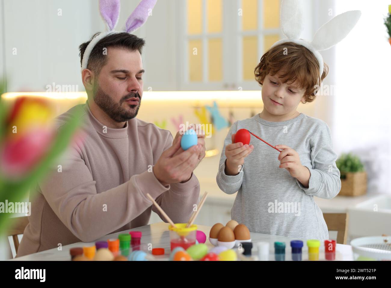 Easter celebration. Father with his little son painting eggs at table ...