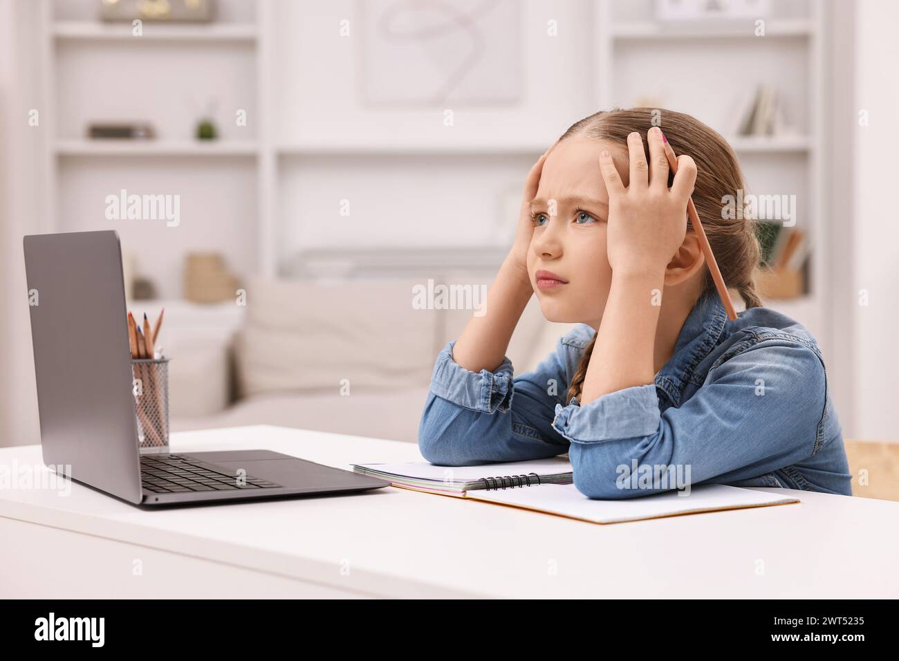 Little girl suffering from headache while doing homework at home Stock ...