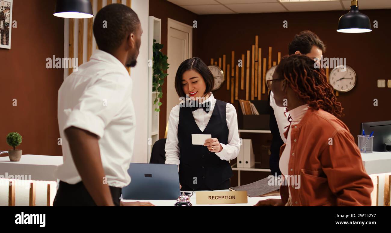 Tourists handing over room access key to friendly asian receptionist at ...