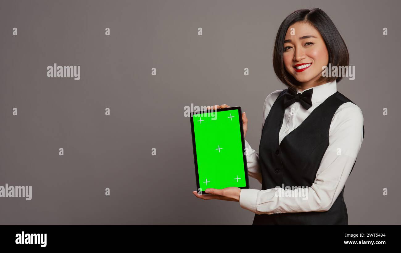 Woman concierge presenting greenscreen display on tablet, showing ...