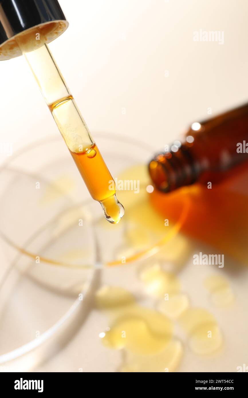 Dripping moisturizing serum from pipette against blurred background ...