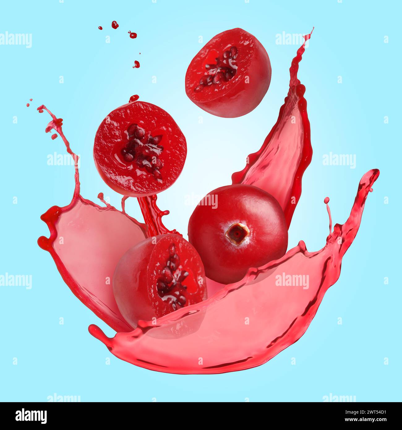Delicious ripe cranberries and splashing juice in air on light blue ...