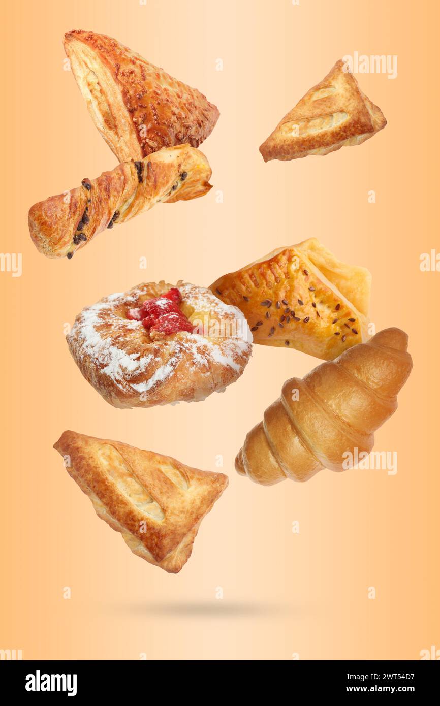 Different tasty puff pastries falling on pale orange background Stock ...