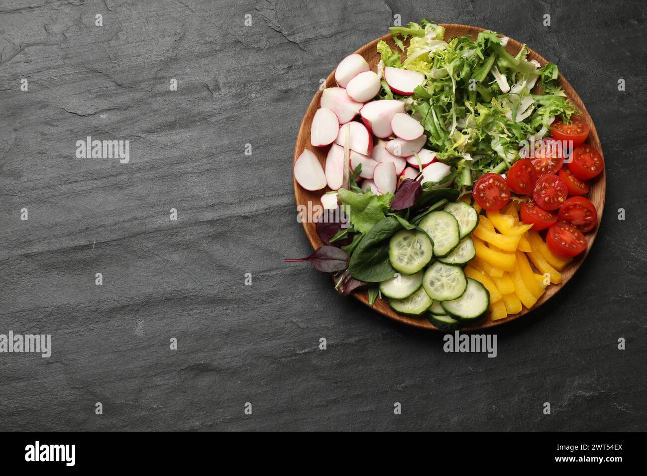 Vegetarian diet. Plate with tasty vegetables on black table, top view ...